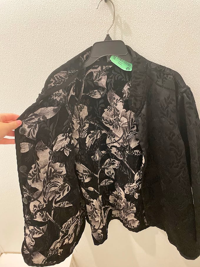 Intricate floral patterns on this vintage jacket tell tales of fashion eras gone by. Someone's special occasion piece awaits its next grand entrance.