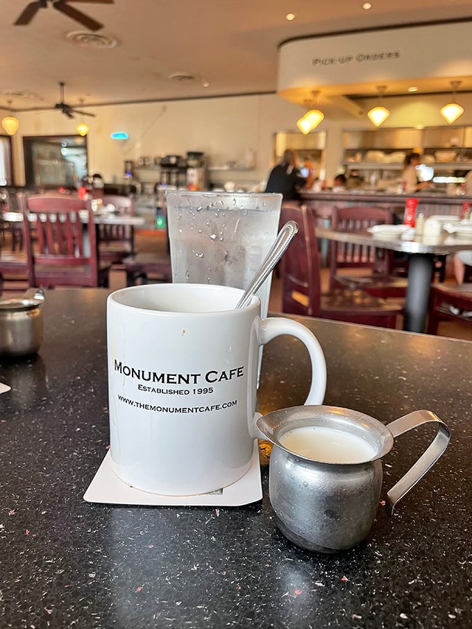 The Monument Cafe mug promises liquid motivation while that silver creamer stands by, ready for its supporting role in your morning ritual.