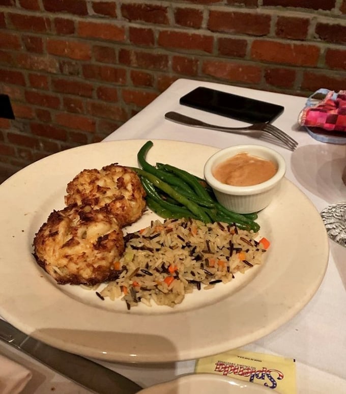 These aren't your average crab cakes—they're golden islands of seafood treasure on a sea of wild rice, with green beans standing sentinel.