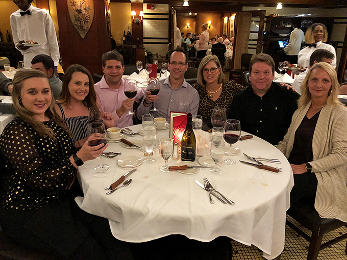 Happy diners raising glasses of ruby-red wine, celebrating that magical moment when good food, good company, and good wine create memories that outlast the meal.