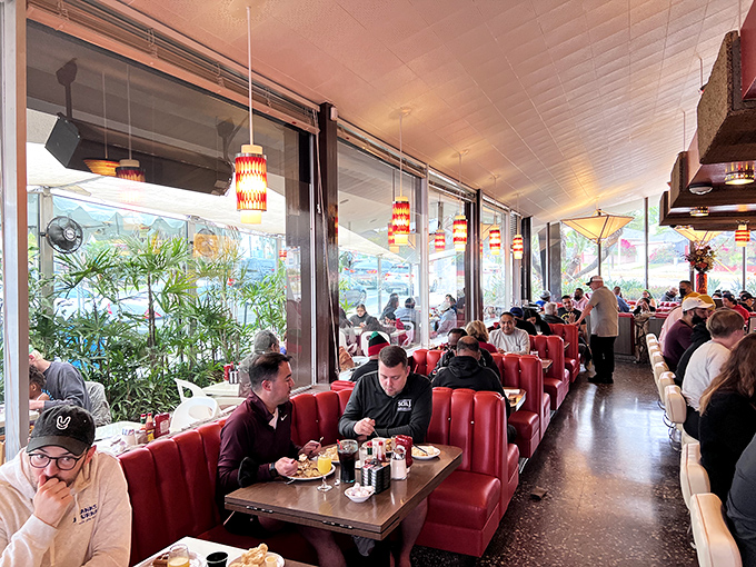 The dining room hums with the symphony of clinking forks and conversation &ndash; red booths filled with people having the best meal of their day.