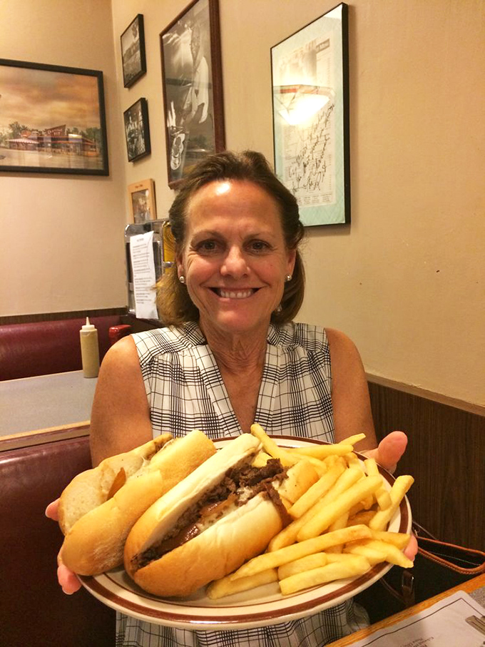 The universal language of burger joy written clearly on this diner's face, holding a plate that couldn't look more appetizing if it tried.