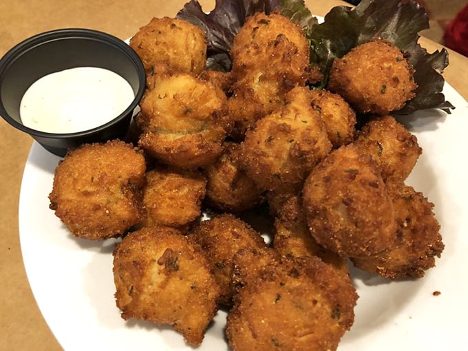 Golden hush puppies with a side of dipping sauce&mdash;crispy on the outside, tender within&mdash;the kind of appetizer that ruins friendships when the last one remains.