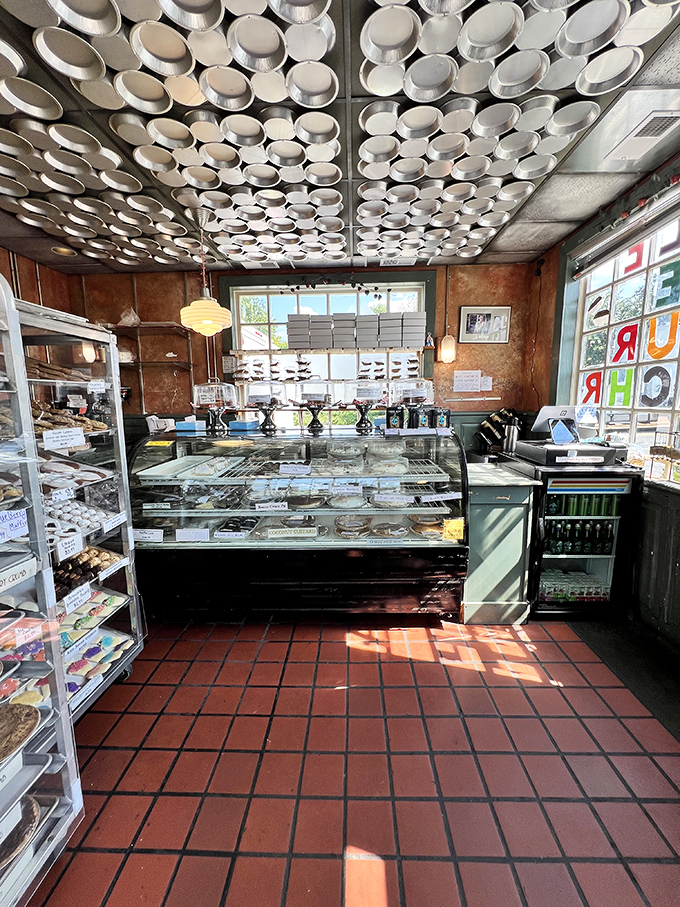 Sunshine streams through windows illuminating pie paradise. The red tile floor and vintage display cases create a time capsule of deliciousness.