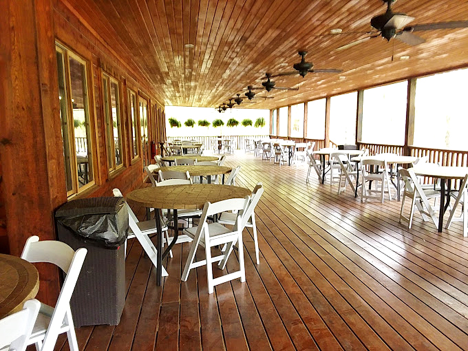 Comfort meets nature on this rustic wooden porch, where ceiling fans stir the air and tables await conversations over coffee and pastries.