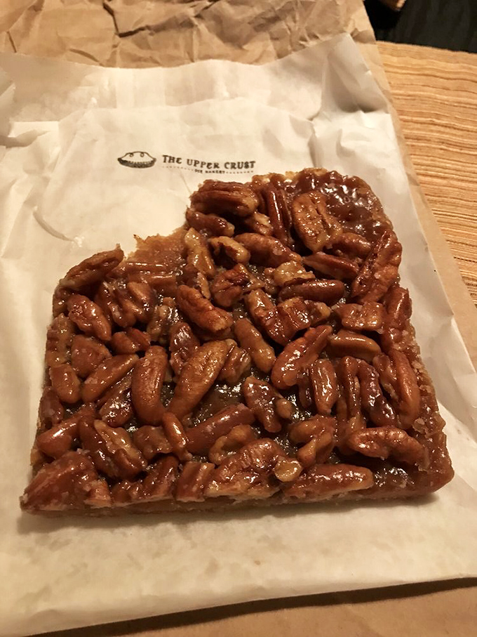 The pecan bar glistens with caramelized perfection. Each pecan is a soldier in a sweet, sticky army determined to conquer your willpower.