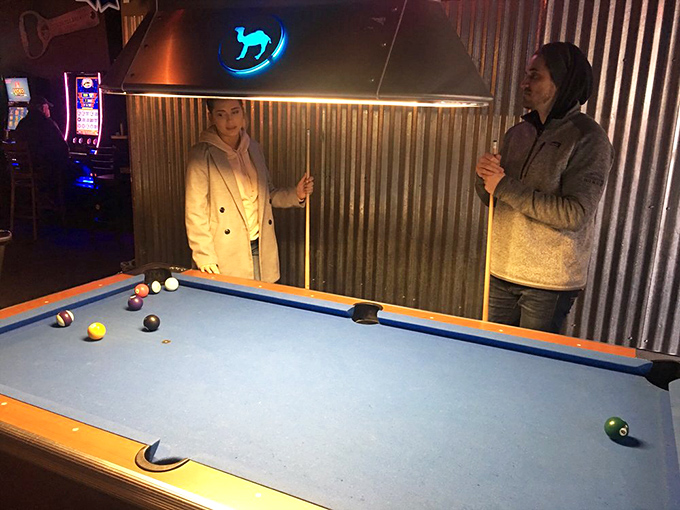 The pool table area – where friendly competition and questionable physics collide under the watchful eye of the blue neon goat.