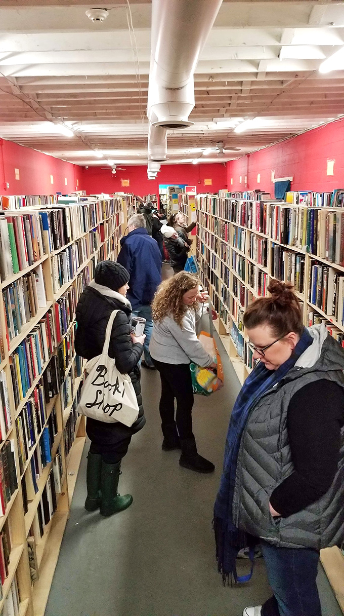 A crimson-walled corridor packed with browsers hunting literary gold. The red room buzzes with the quiet electricity of discovery.