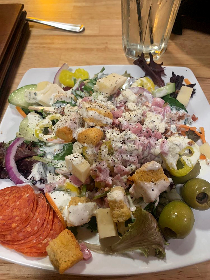 The house salad bursts with fresh vegetables, olives, and house-made dressing&mdash;a vibrant prelude to the heartier courses that follow.