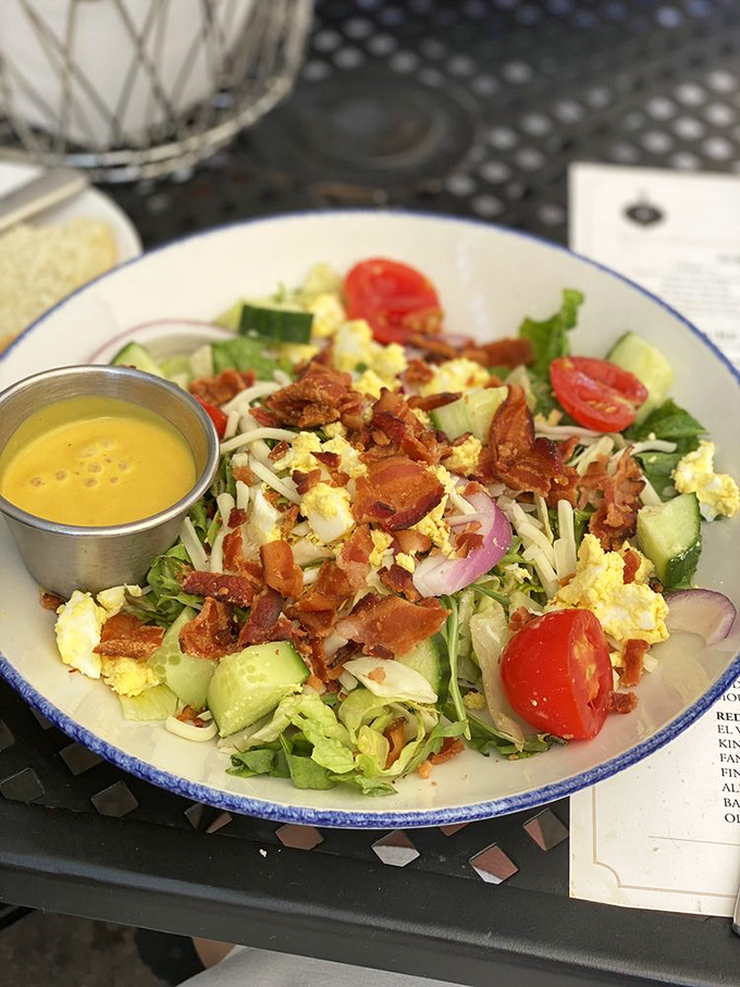 A house salad that defies the "boring salad" stereotype with crisp vegetables, bacon, and egg creating a garden party in a bowl.