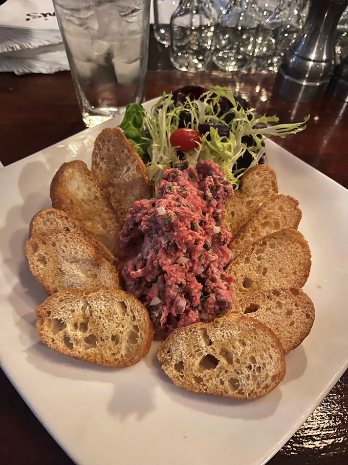 Steak tartare surrounded by toast points like a meaty sunburst &ndash; raw beef never looked so civilized or tempting.
