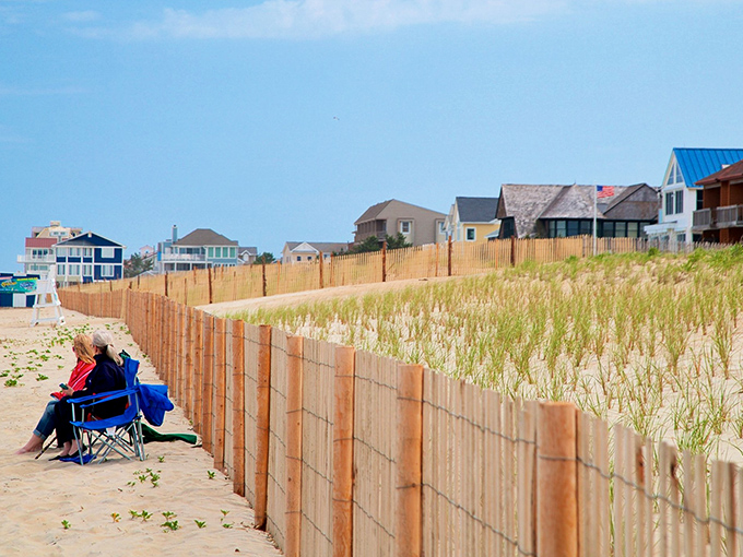 Beach chairs and protective dunes create nature's perfect theater, where the daily show features waves, seagulls, and the occasional dramatic sandcastle collapse.
