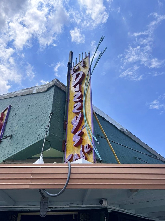 The vertical sign beckons like a lighthouse for hungry souls, promising salvation in the form of perfectly fried deliciousness.
