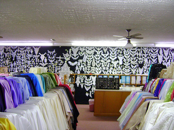 The bridal section, where yards of white lace hang like frozen waterfalls, ready to transform "I think I'll make my own dress" into "I do."