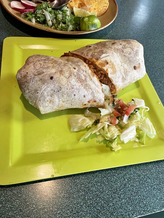 This burrito on a lime-green plate isn't just food &ndash; it's edible architecture with structural integrity that would impress any engineer.