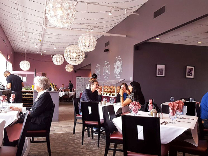 The dining room hums with the universal language of good food, as patrons engage in that sacred ritual of breaking naan together.