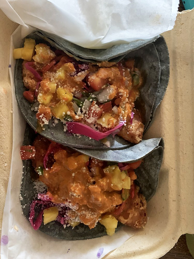 These street-style tacos arrive in their blue corn tortilla jackets—dressed up with pickled onions and fresh cilantro like they're heading to a fiesta.