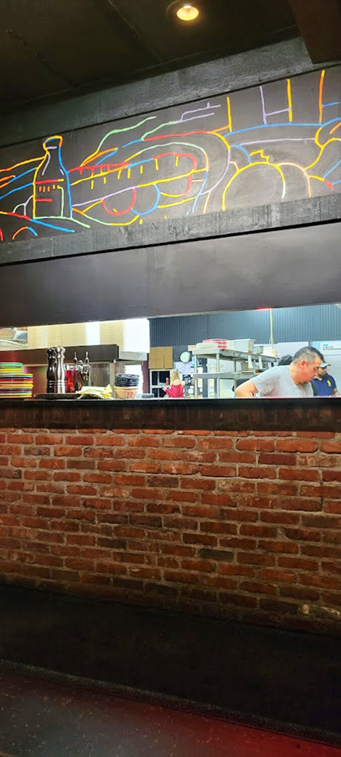 A glimpse into the kitchen where the magic happens. That neon-outlined pizza art isn't just decoration&mdash;it's a mission statement.