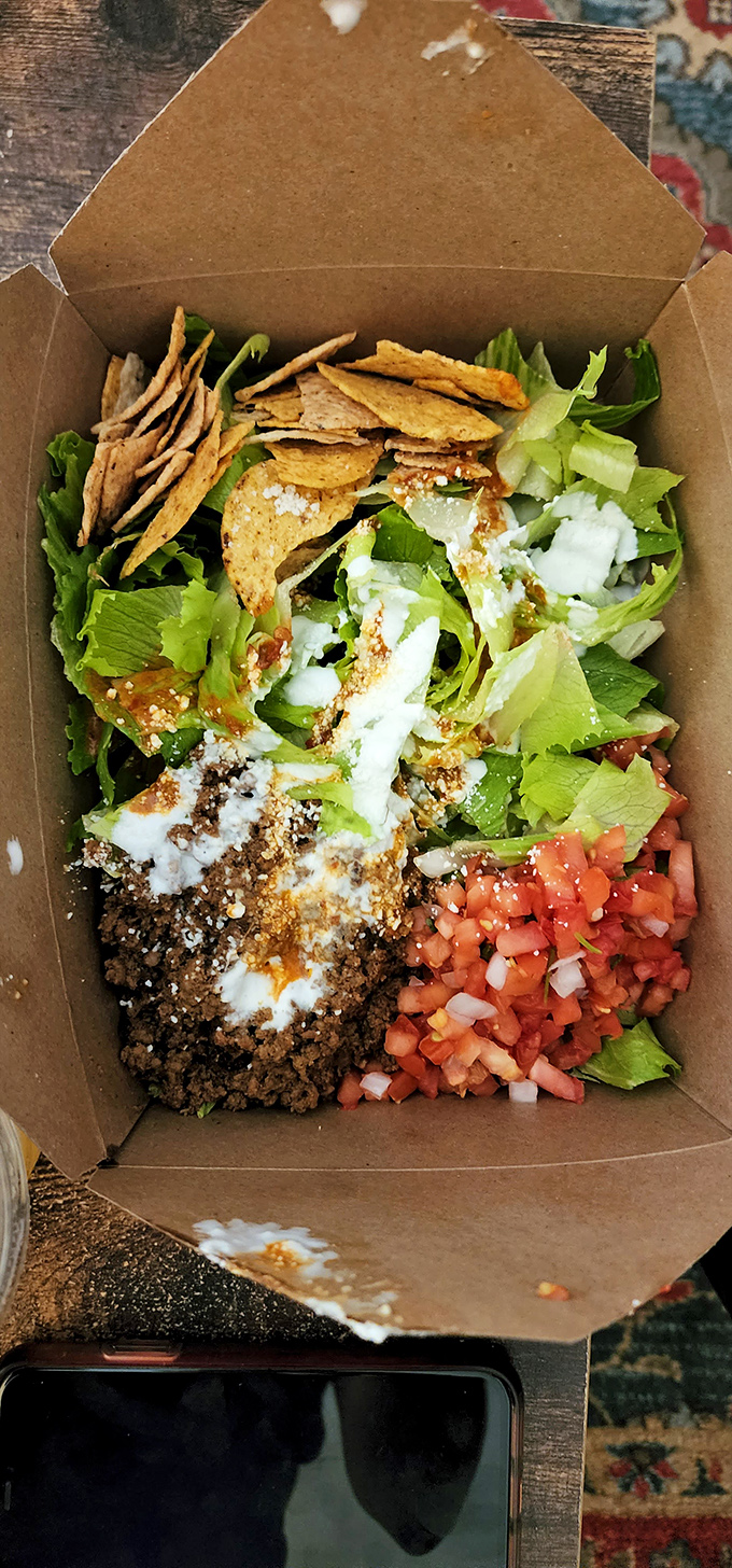 A taco salad that's having an identity crisis in the best possible way&mdash;part nachos, part salad, all delicious in its eco-friendly cardboard home.