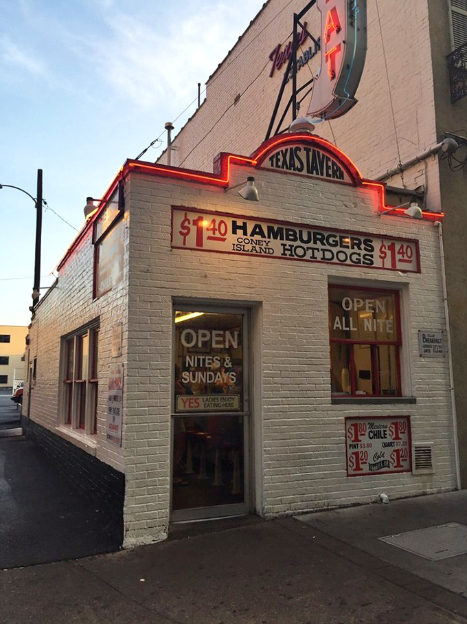 As dusk settles, the neon glow of Texas Tavern becomes a lighthouse for the hungry, promising "OPEN ALL NITE" salvation to night owls and early risers alike.