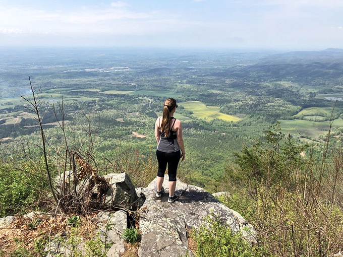 Standing on this rocky outcrop transforms visitors into temporary mountain monarchs, surveying a kingdom of rolling hills that reach toward Tennessee like green waves.