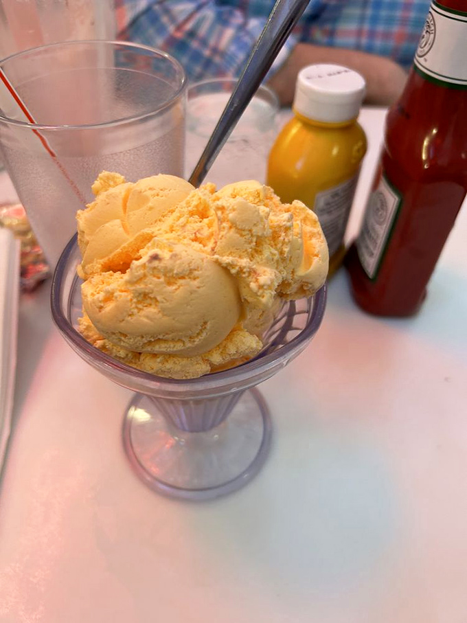 Sunshine-hued orange-pineapple ice cream sits in a classic glass dish—unpretentious perfection that needs no modern improvement.