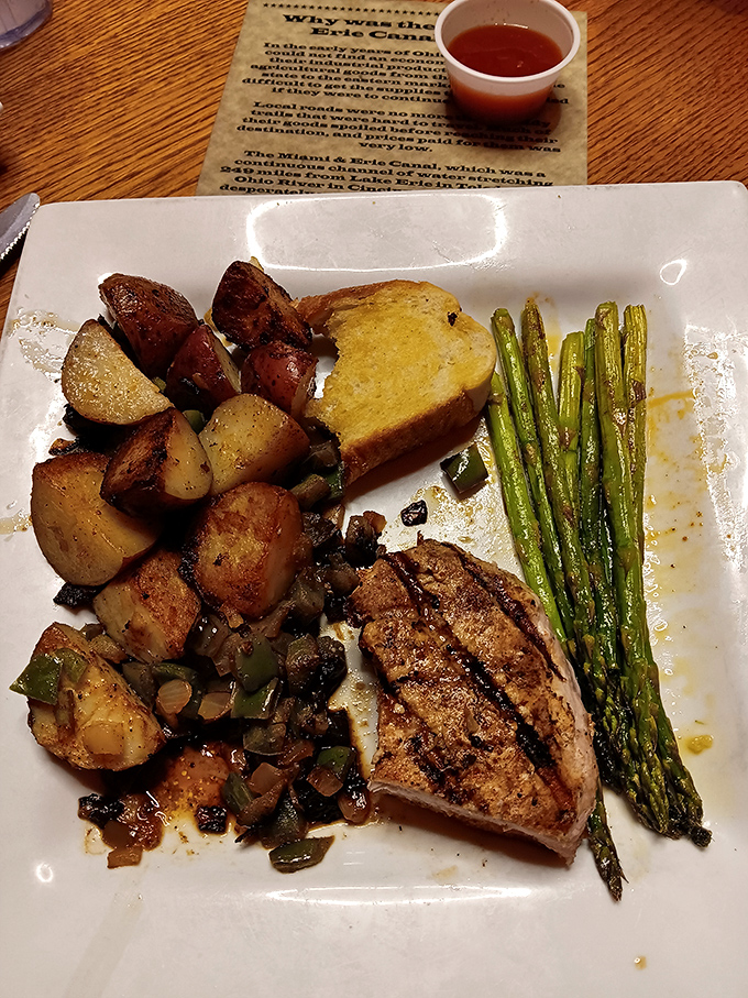 A perfectly grilled pork chop with roasted potatoes and asparagus &ndash; the plate that whispers, "Yes, they do more than just steak, and they do it brilliantly."