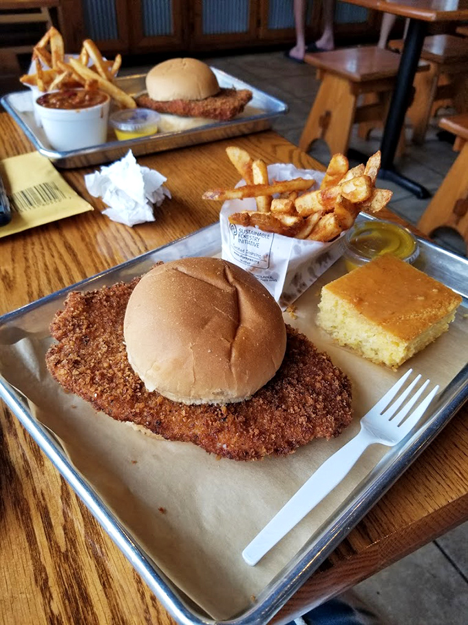 The pork tenderloin sandwich—an Iowa classic that's been breaded, fried, and served with the kind of cornbread that makes grandmothers nod in approval.