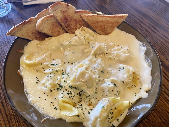 Ravioli swimming in a sea of creamy goodness. Those toasted bread triangles aren't just garnish—they're essential cheese-sauce delivery vehicles.
