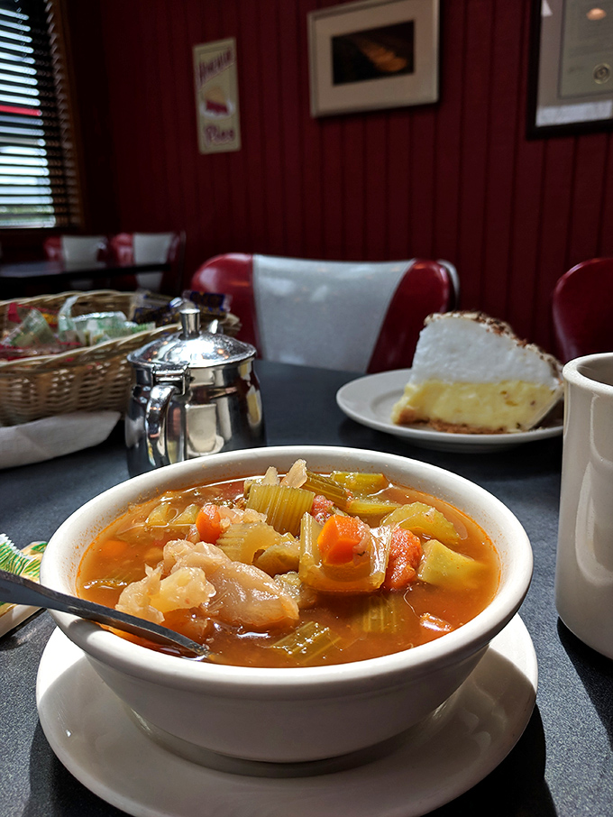 A bowl of soup that's giving chicken noodle an identity crisis. With a slice of cream pie waiting patiently in the background like a perfect closing argument.