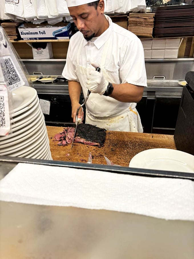 The art of hand-slicing perfected. This isn't just sandwich preparation; it's a performance that's been running continuously since the Spanish-American War.