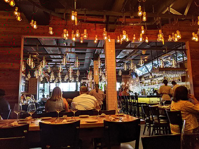 The dining room pulses with energy under those signature bulbs. You can almost taste the conversations happening around perfectly cooked steaks.