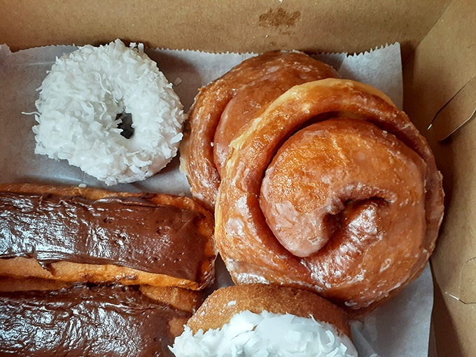 The holy trinity of donut perfection: coconut-topped, chocolate-glazed, and cinnamon swirl. A cardboard box never held such potential for joy.
