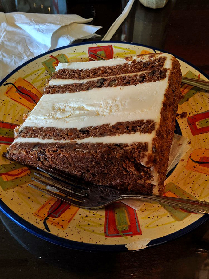 A slice of carrot cake so massive it deserves its own zip code. That cream cheese frosting layer is thicker than a Manhattan phone book.
