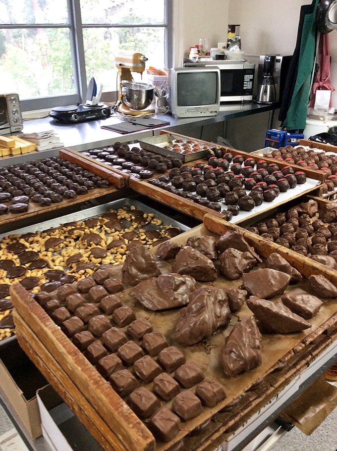 Behind the scenes where the magic happens. Wooden trays lined with future happiness in various stages of chocolate transformation &ndash; patience never looked so delicious.