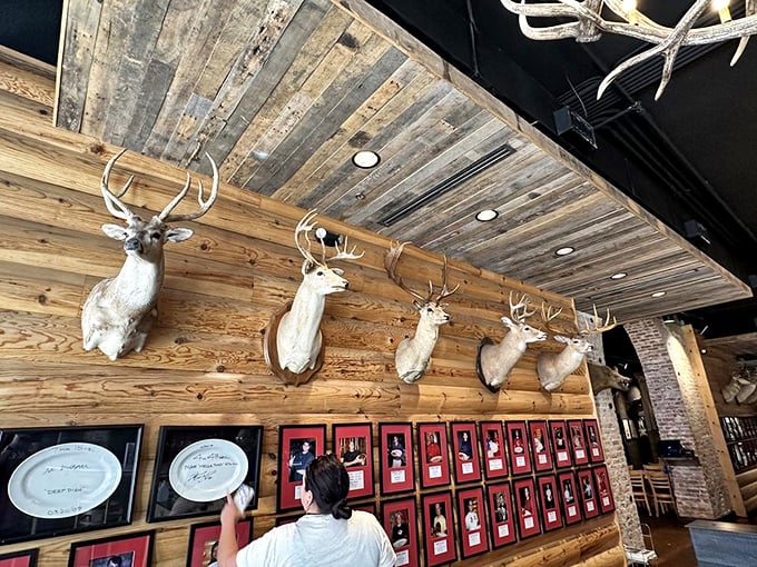 The Wall of Fame showcases triumphant diners who conquered culinary mountains, while mounted deer heads look on with what appears to be respect.