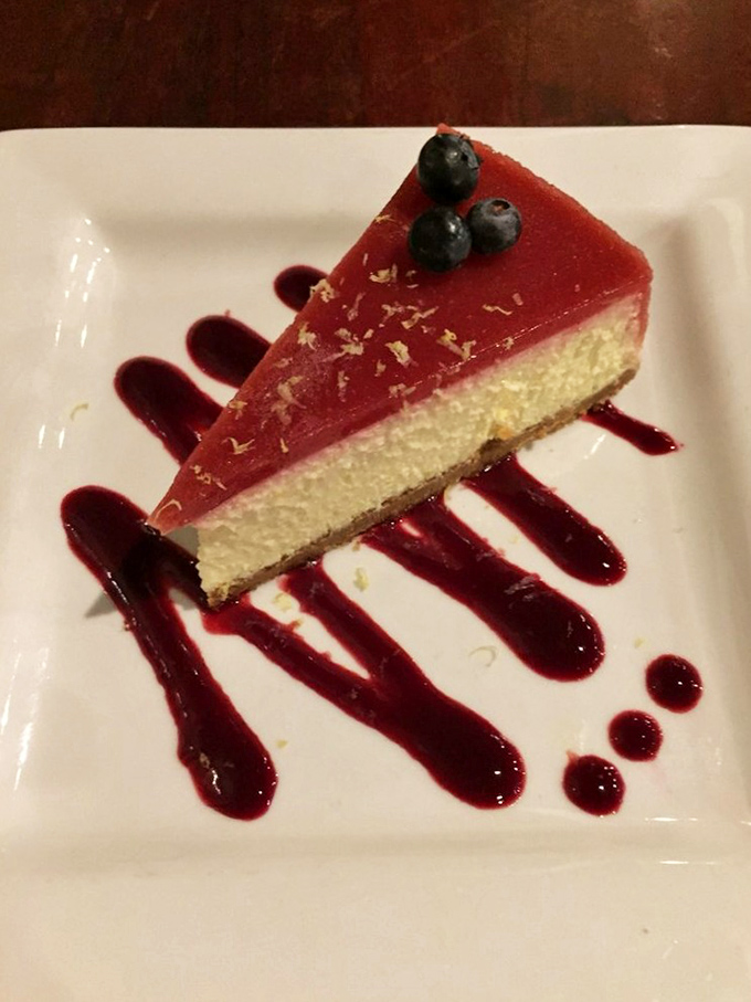 A slice of heaven in hell: Berry-topped cheesecake drizzled with fruit coulis &ndash; the sweet finale that proves even the underworld has its heavenly moments.