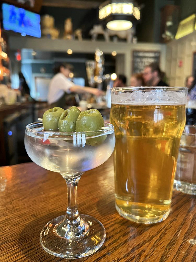 The perfect pub pairing&mdash;a crystal-clear martini with olives standing at attention beside a golden pint of beer. Civilization reached its peak the moment these two drinks could coexist peacefully.