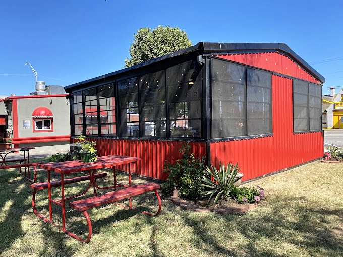 This red-trimmed patio enclosure isn't just additional seating&mdash;it's a greenhouse for growing happiness, one burger conversation at a time.