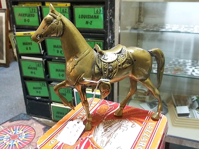This brass horse figurine stands proudly atop vintage board games, ready to gallop into your collection. Notice the cabinet of state-labeled drawers behind.