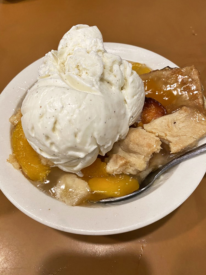 Peach cobbler crowned with ice cream melting into warm, golden fruit&mdash;proof that dessert isn't an afterthought but a grand finale worthy of applause.