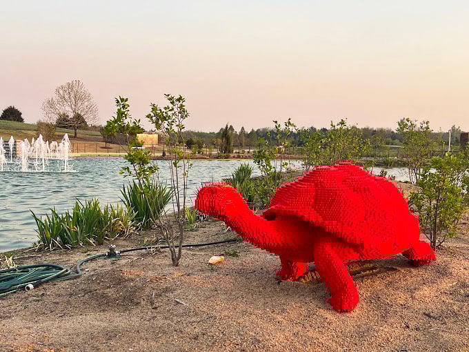This bright red LEGO-like turtle proves that art and whimsy have their place in the garden, standing guard by the water like a cheerful sentinel.