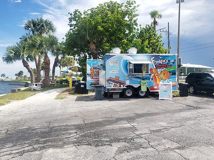 Fredgie's colorful food truck sits like a tropical mirage, promising hot dog nirvana with palm trees and water views as your dining companions.
