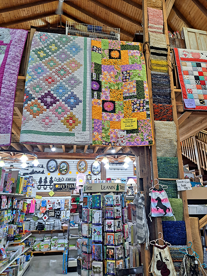 Handcrafted quilts hang like colorful banners from wooden rafters, showcasing the artistic possibilities awaiting fabric enthusiasts below.