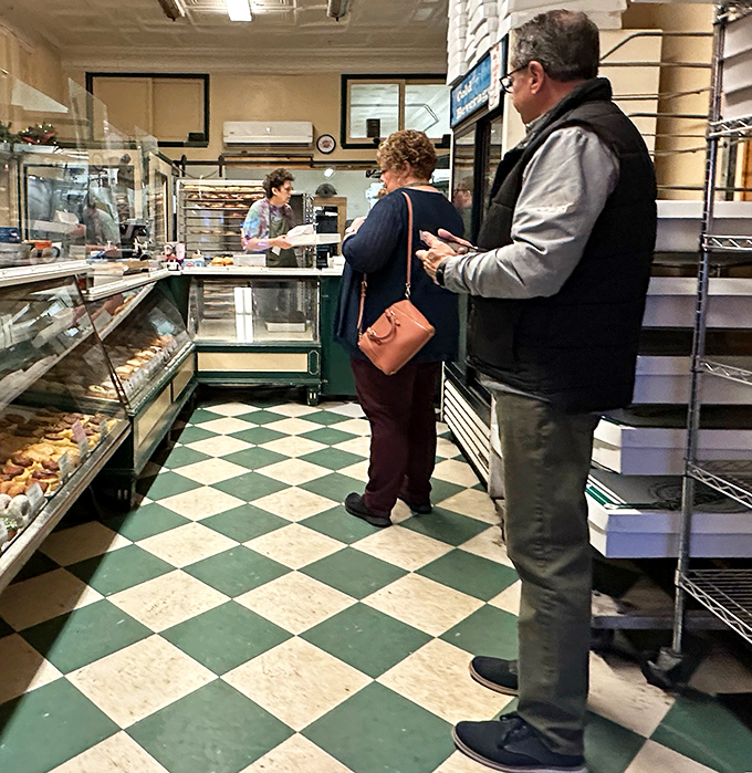 The classic checkerboard floor says "timeless," while the display cases whisper "resistance is futile." Donut democracy in action.