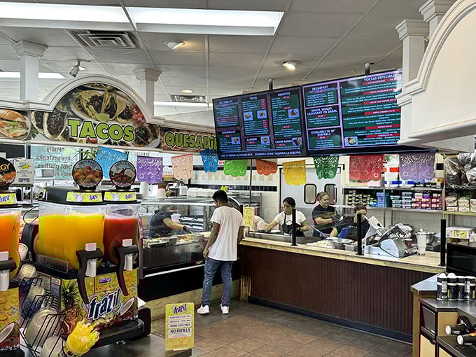 Behind the counter, culinary magic happens as staff prepare fresh Mexican classics while colorful papel picado banners dance overhead, creating an instant fiesta atmosphere.