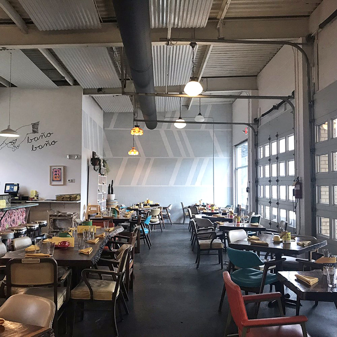Industrial chic meets breakfast paradise. The garage doors open to create an airy space where conversations flow as freely as the coffee, minus the oil stains of its previous life.