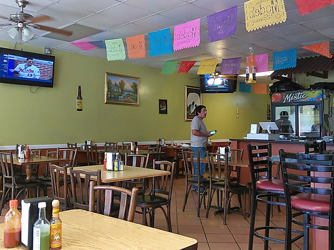 Colorful papel picado flags dance overhead while wooden tables and yellow walls create that "grandma's house meets Mexican fiesta" vibe we all secretly crave.