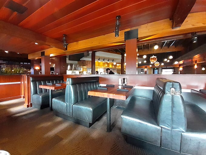 Warm wood ceilings, teal leather booths, and strategic lighting create the perfect atmosphere for both celebration and Tuesday night comfort.