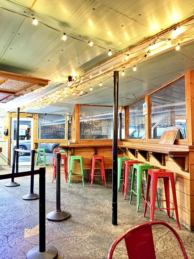 String lights create a warm glow over colorful metal stools, where strangers become friends united by their love of exceptional fried chicken.